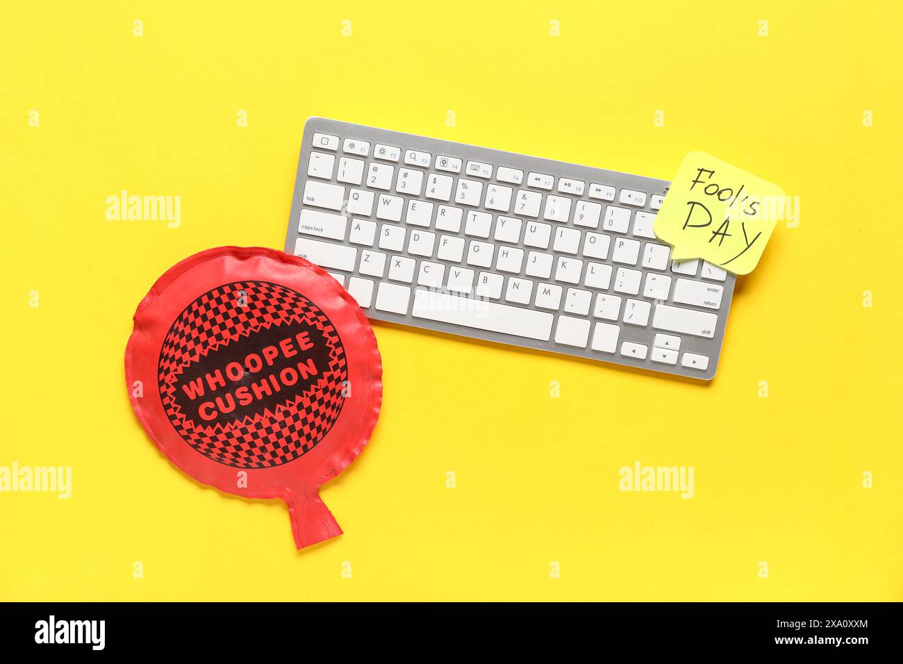 Computer keyboard, sticky note and whoopee cushion on yellow background ...
