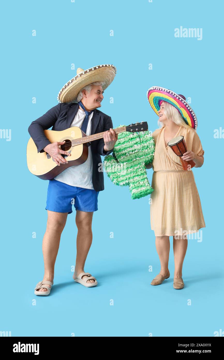 Mature business people in sombrero hats with Mexican pinata playing ...