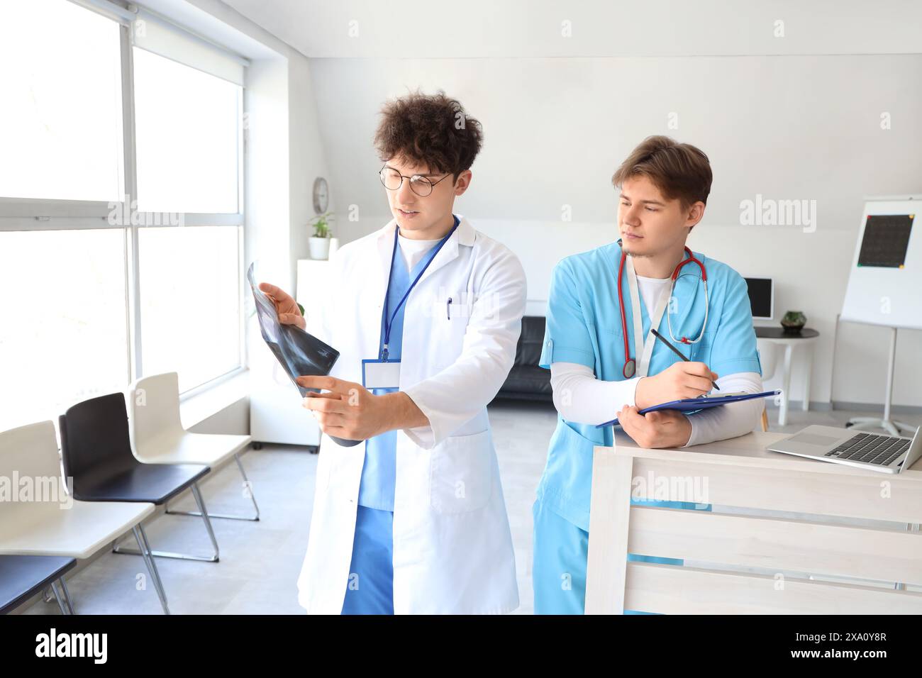 Male medical interns examining x-ray scan of lungs at reception in ...