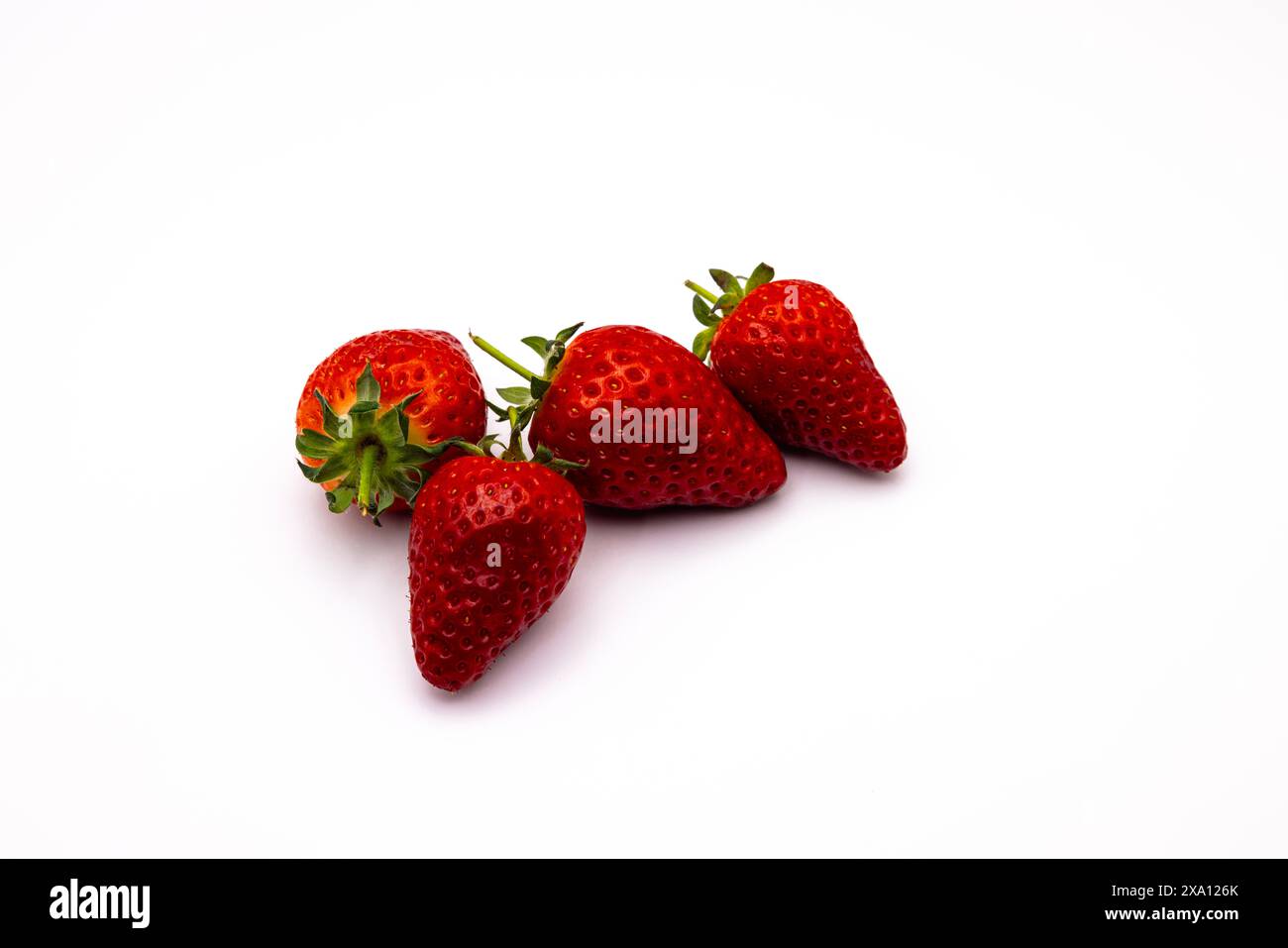 Three strawberries on a white surface with tops tilted Stock Photo - Alamy