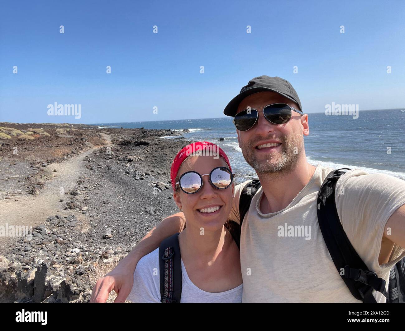 Couple on cliff overlooking beach with rocky shoreline in background ...