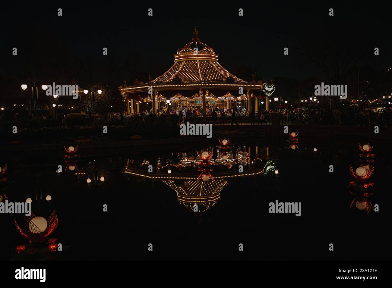 The carousel at night, its lights reflecting in the river, creating a ...