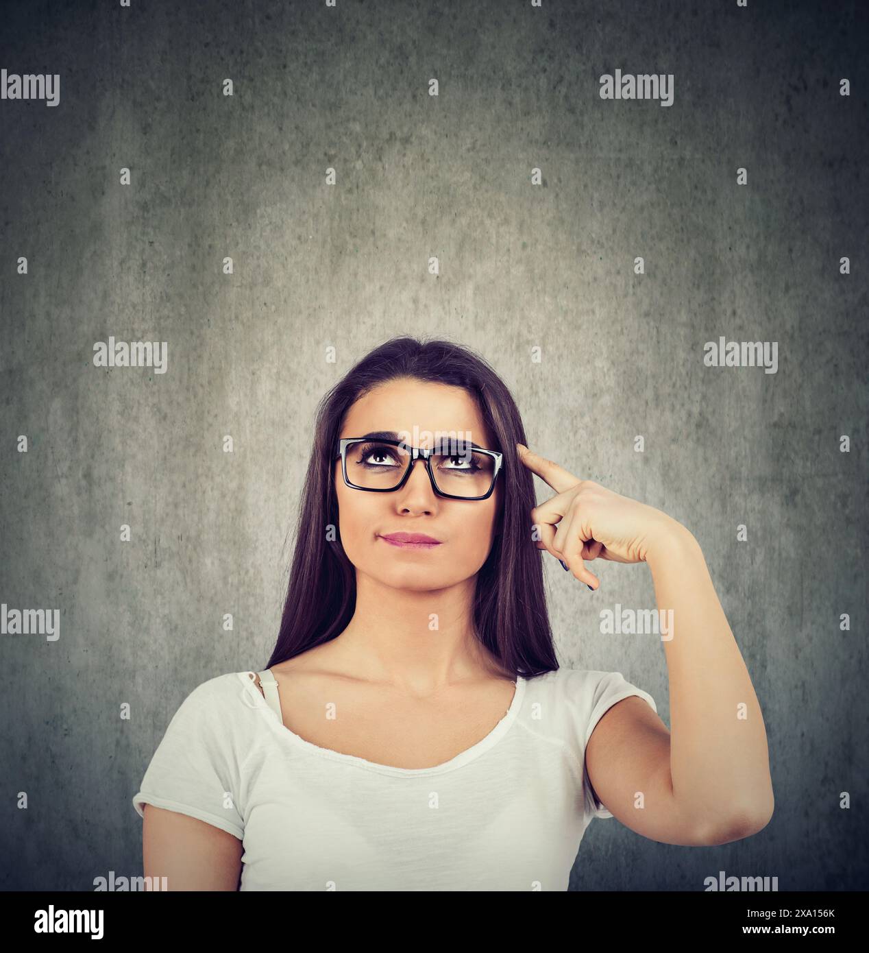 Thinking perplexed woman looking up isolated on gray wall background ...