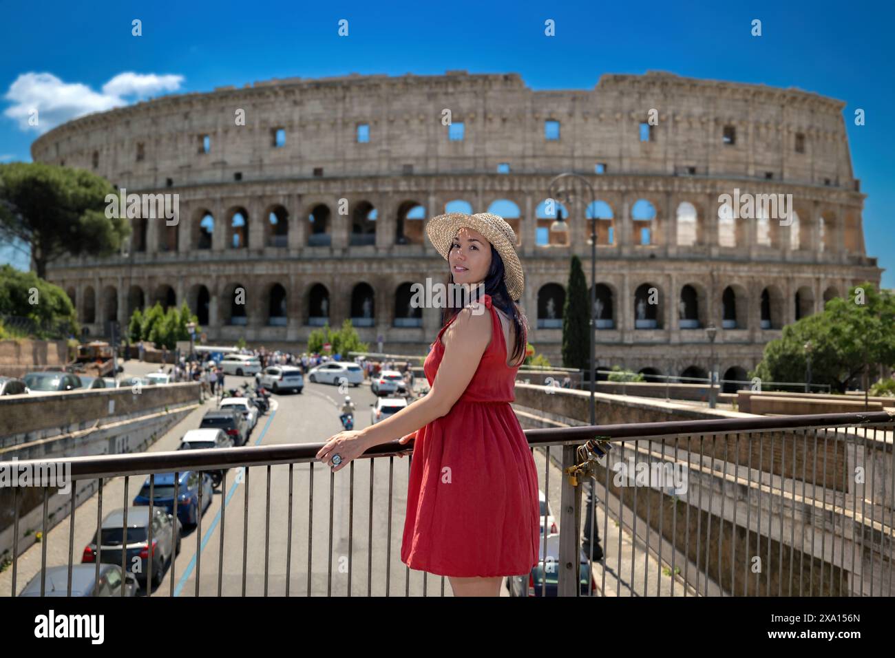 Brunette girl in a straw hat and a red dress admires the ancient ...
