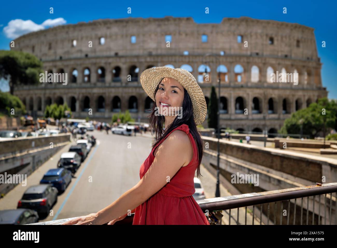 Brunette girl in a straw hat and a red dress admires the ancient ...