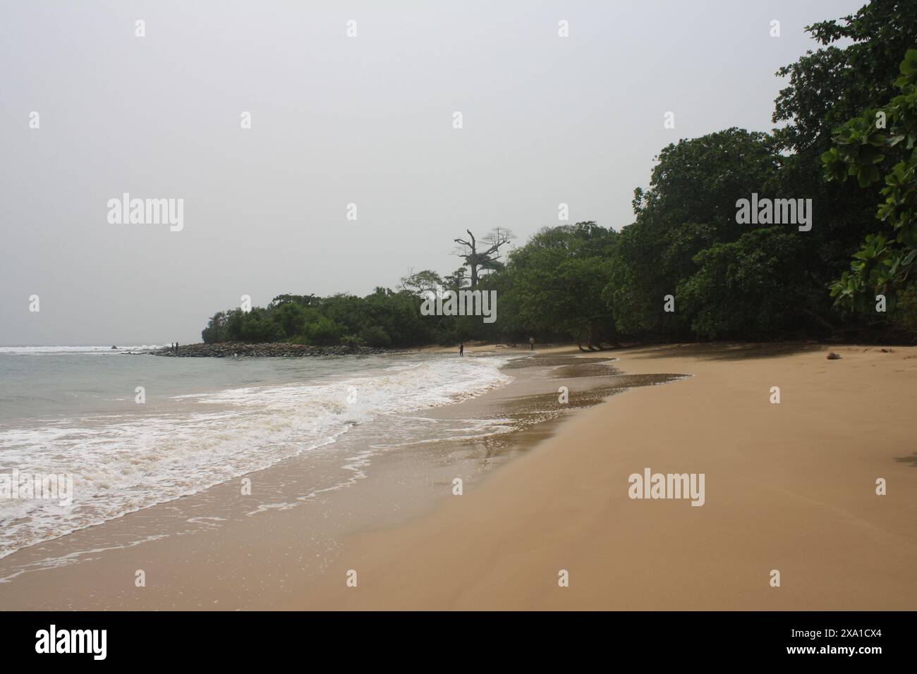 A remote beach featuring a rocky outcrop extending into the ocean. The ...