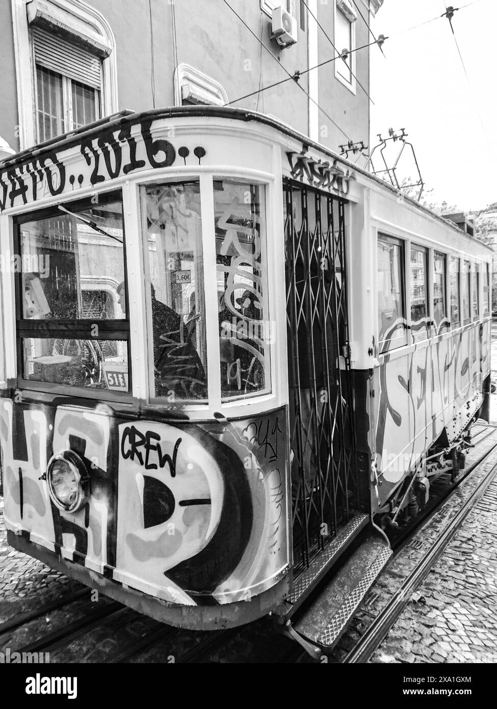 Graffiti-covered vintage tram on city street by building Stock Photo ...