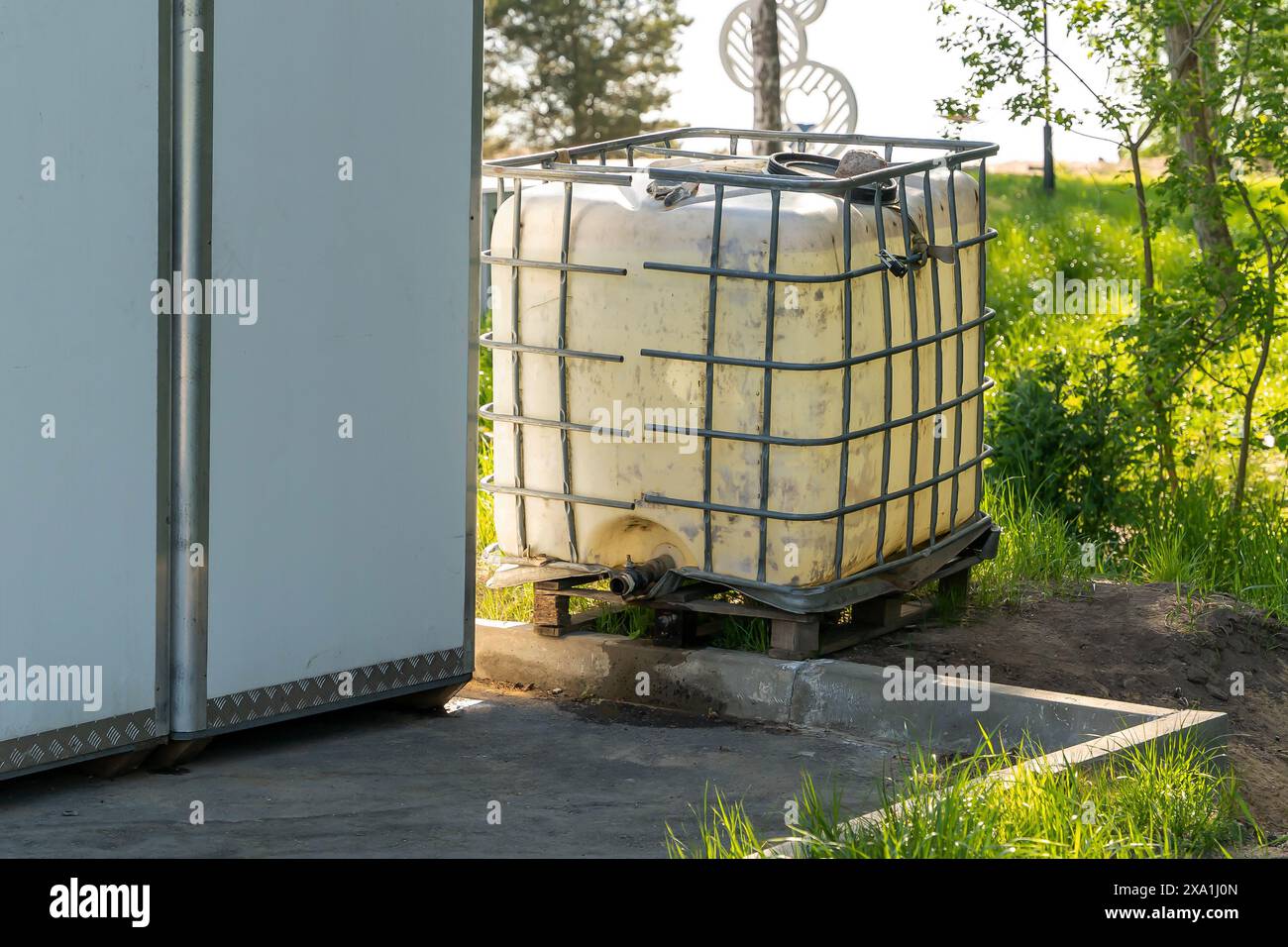 A large white plastic water tank sits on a pallet near a building Stock ...