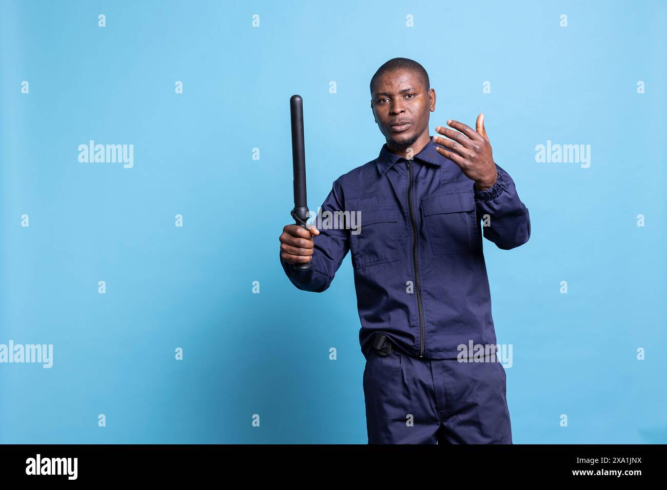 Security guard with a baton in his hand calling people over, asking ...