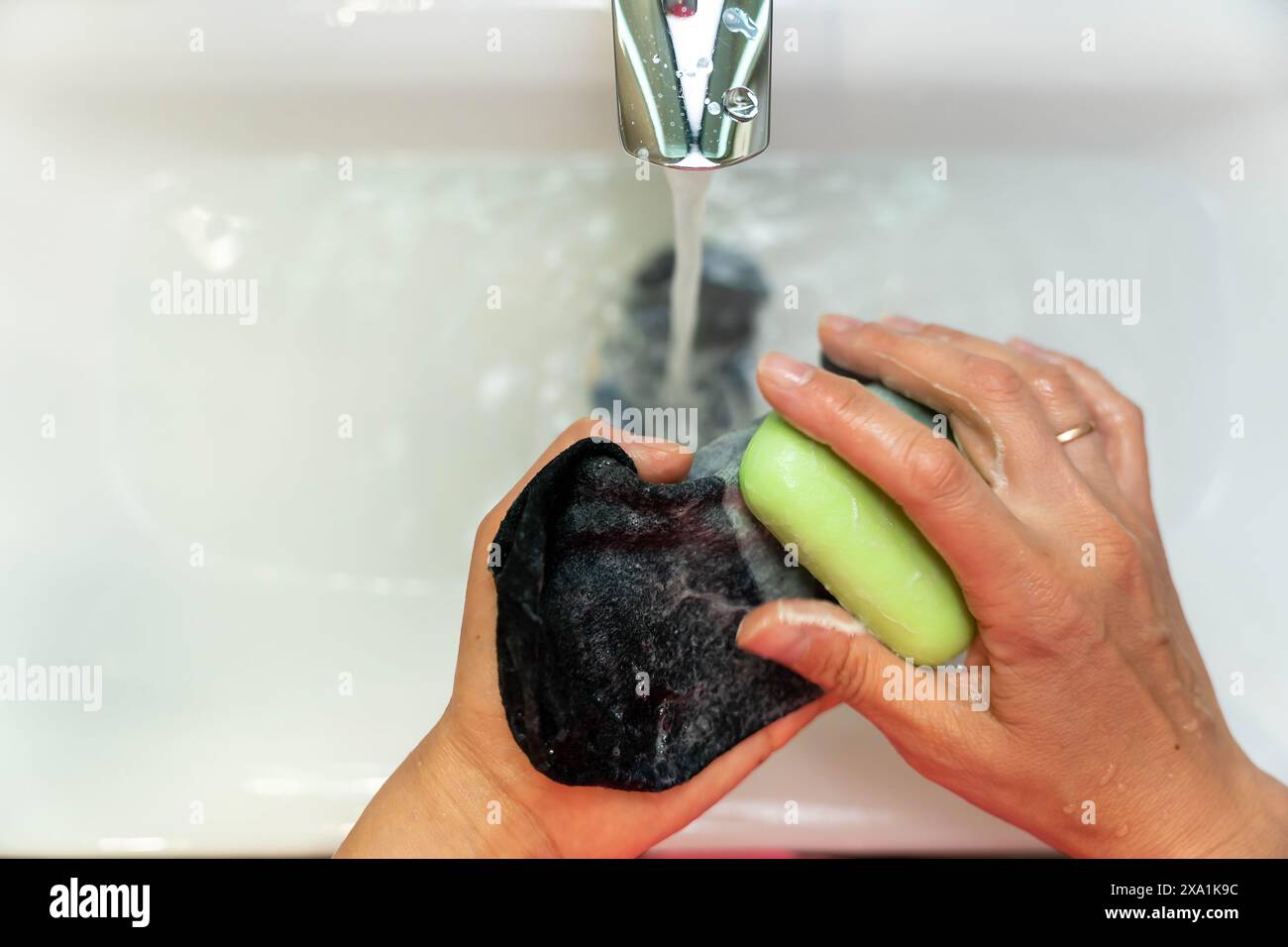 A person hand washing black socks in a bathroom sink with soap Stock ...
