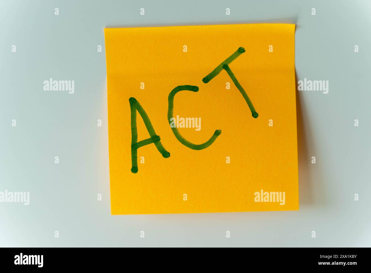 A yellow sticky note on a white fridge with the word ACT written on it ...