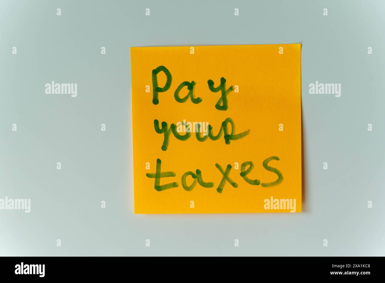 A yellow sticky note with the handwritten message Pay Your Taxes Stock ...