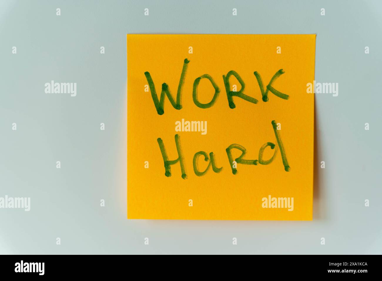 A yellow sticky note with green handwriting that reads Work Hard Stock ...