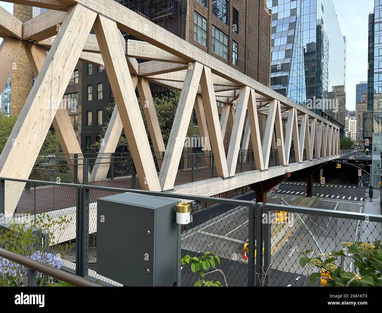 A wooden bridge spanning a city road with modern buildings in the ...
