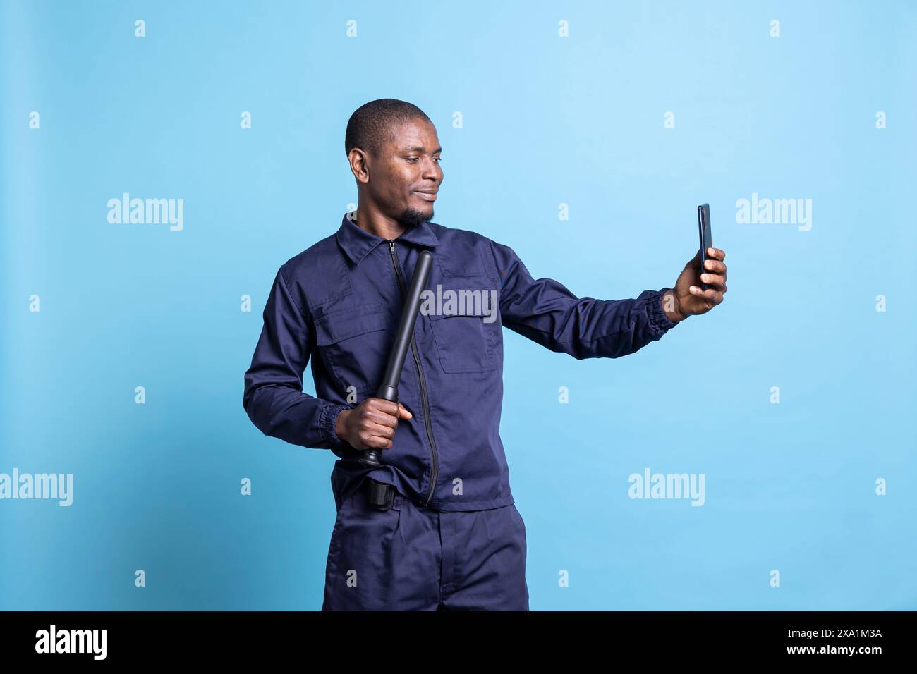 Smiling security agent taking photos with his baton on camera, using a ...