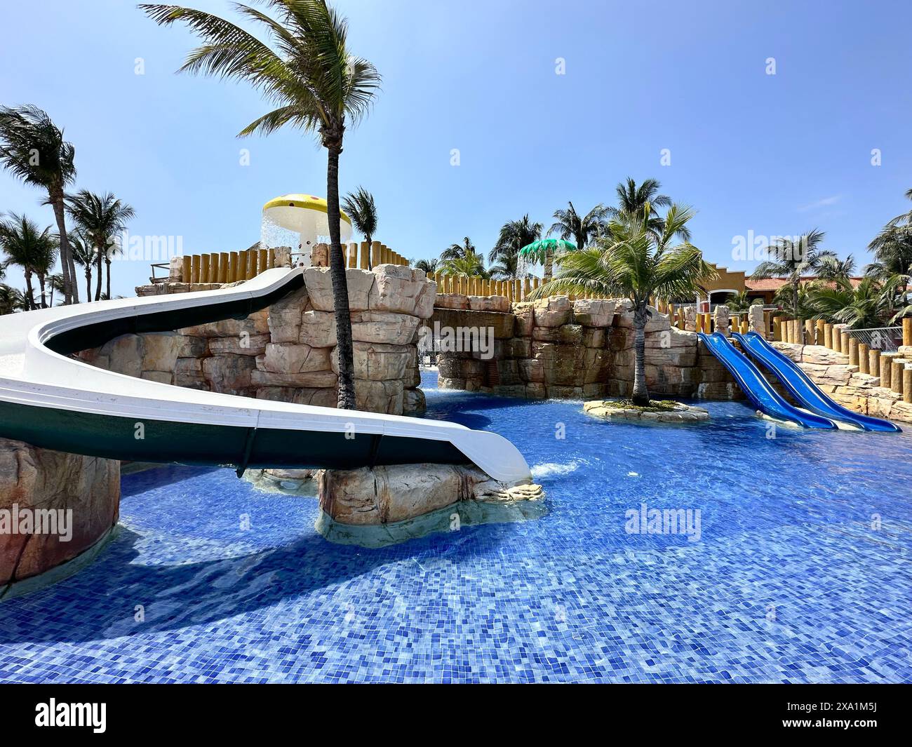 Swimming pool with water slide, artificial waterfall, and rocks at ...