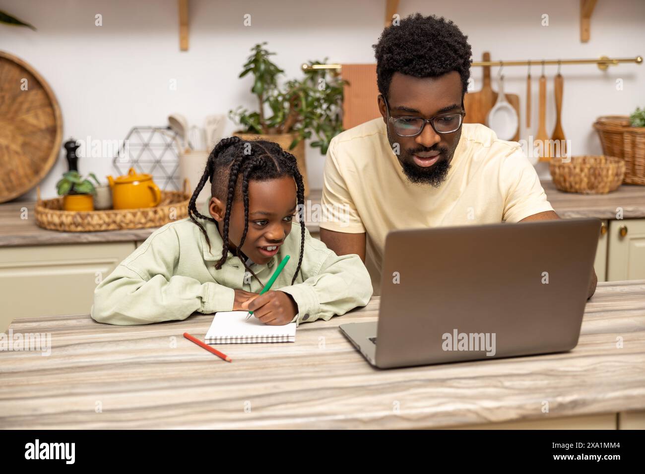 African American father helps his daughter with lessons during distance ...