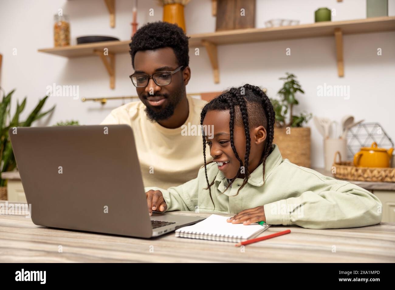 African American father helps his daughter with lessons during distance ...