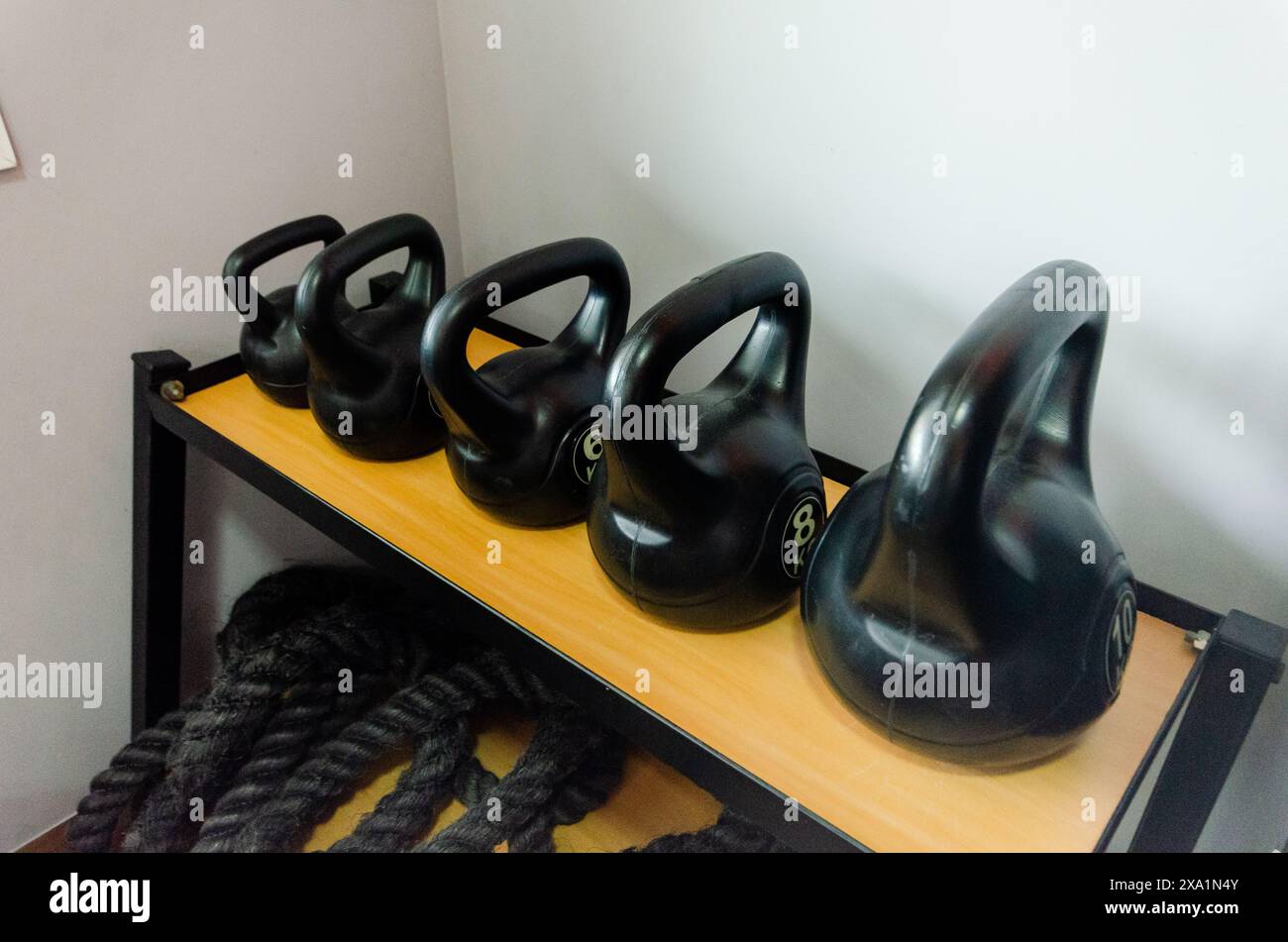 Three kettlebells showcased on a shelf with a rope Stock Photo - Alamy