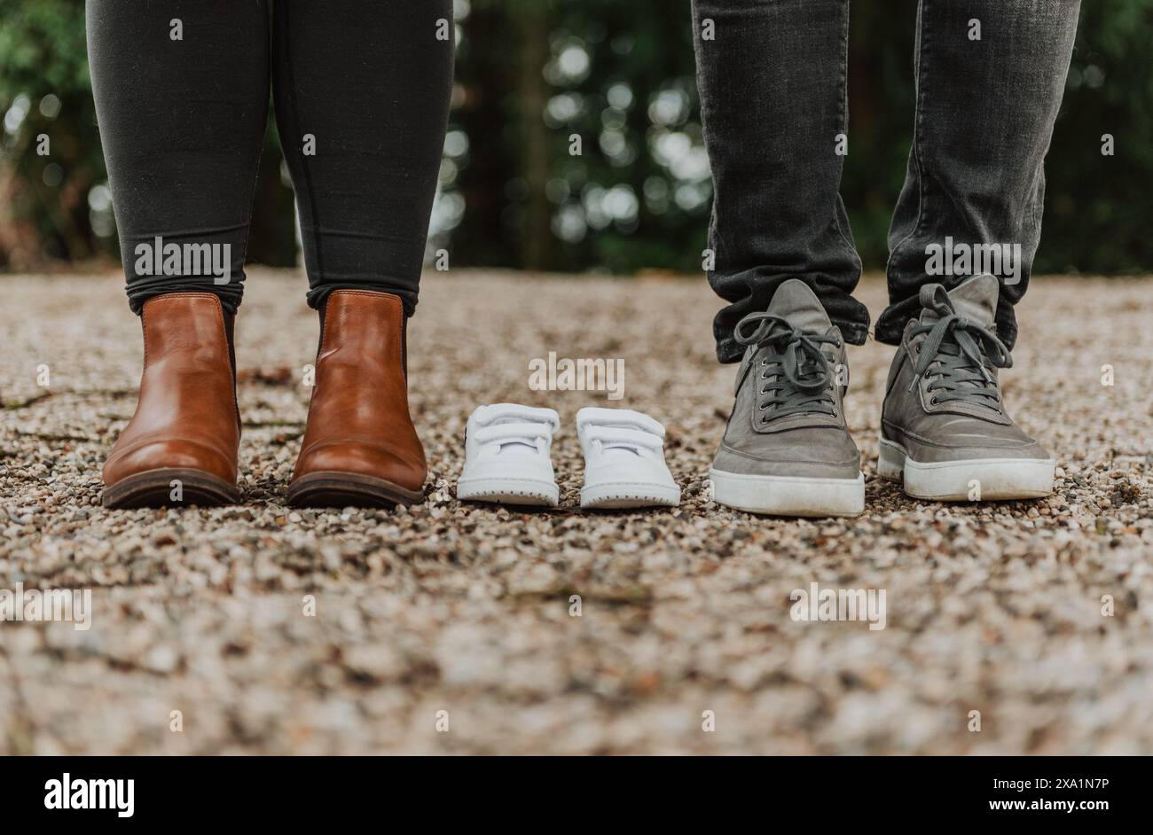 Future mother and father standing next to white baby sneakers during a ...