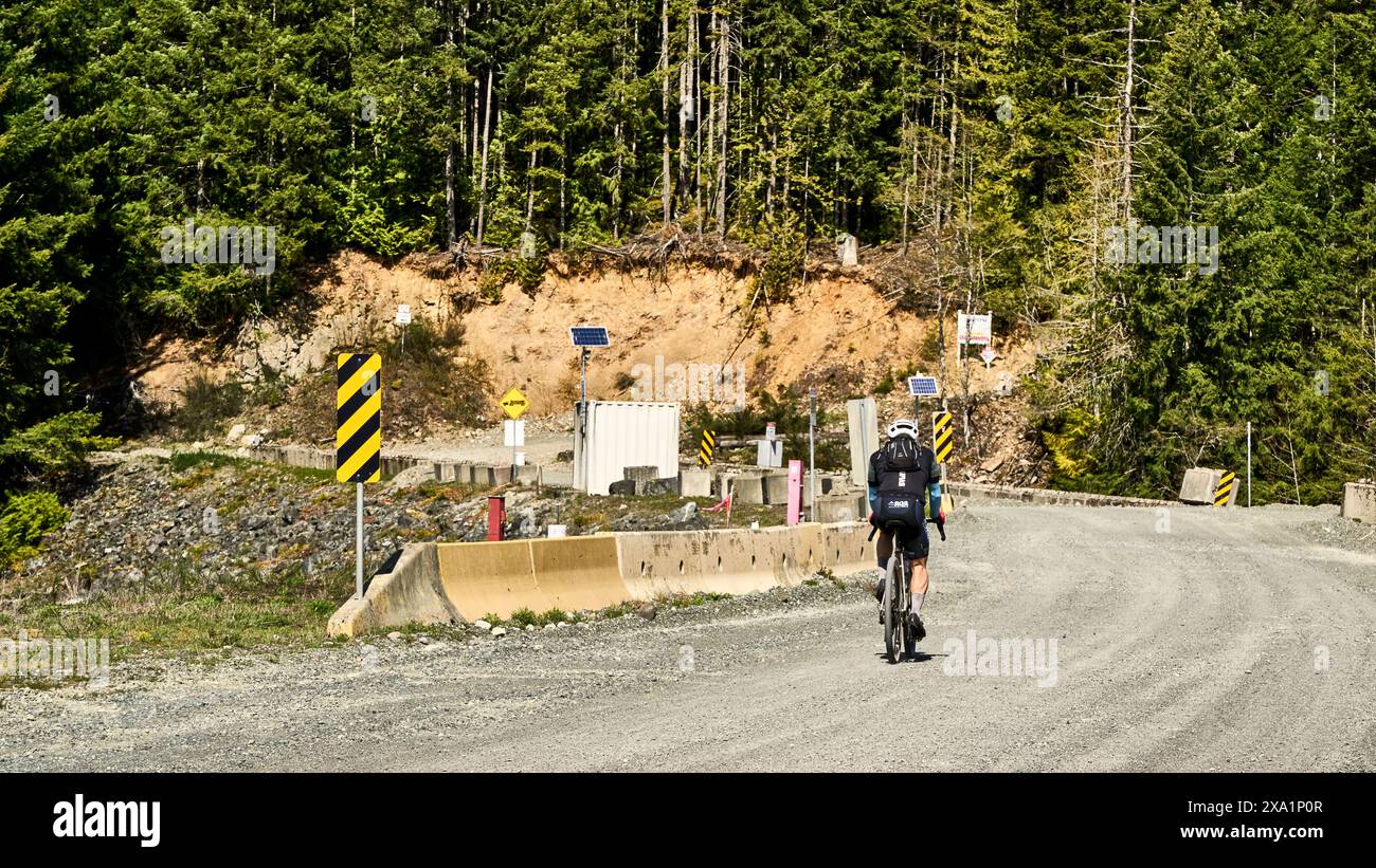 A mountain biker in a race going down a logging road and around a bend ...