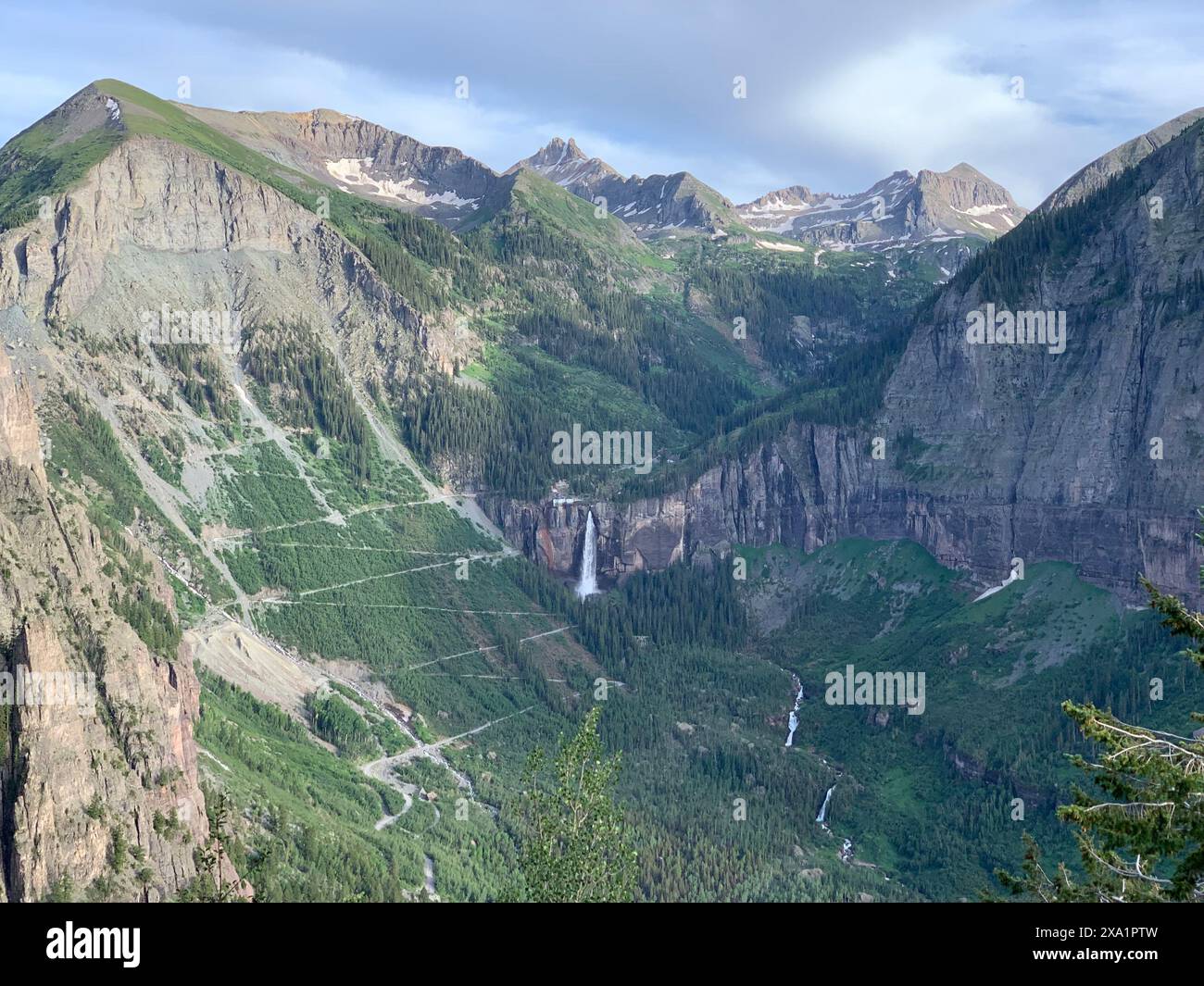 A scenic valley surrounded by towering mountains with a trail leading ...