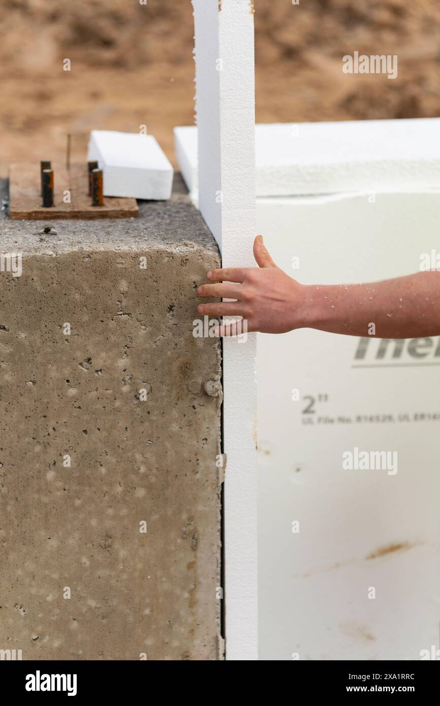 A man working on a concrete wall with polyfoam at an industrial ...