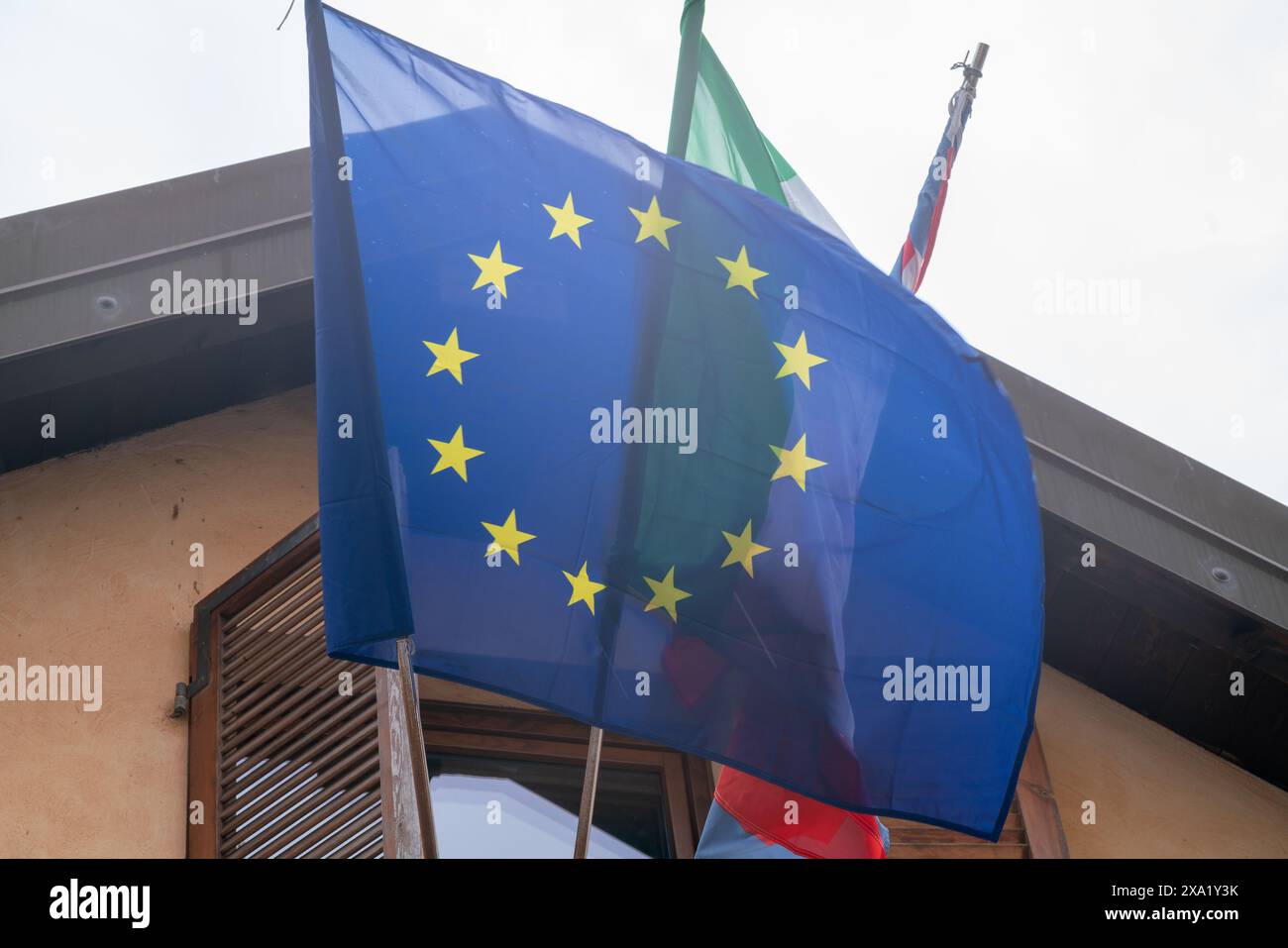 the flag of the European Union flies in the foreground, the flags of ...