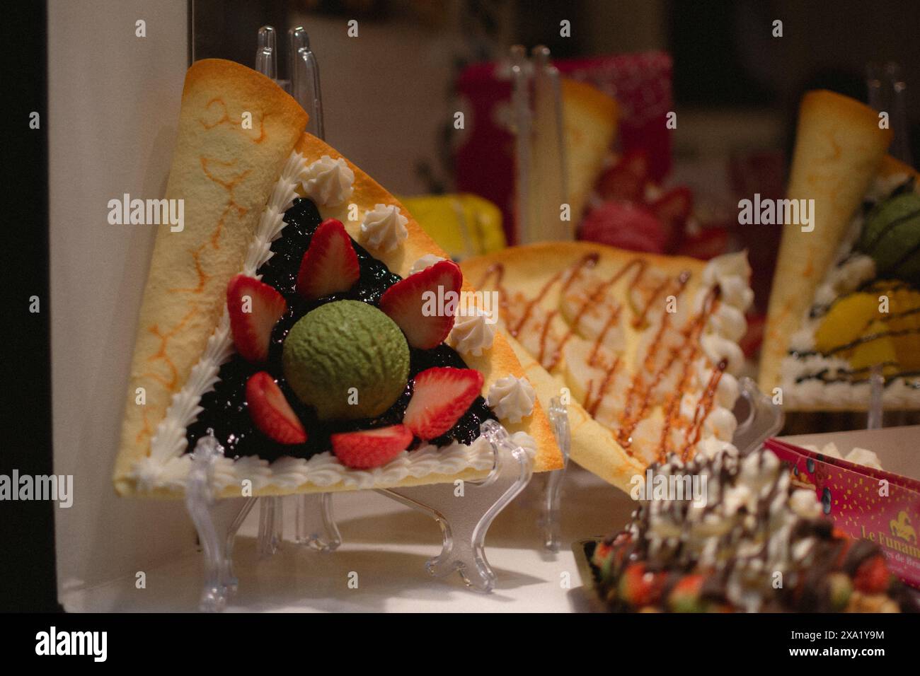 A cake with assorted fruits and chocolate on a transparent display ...