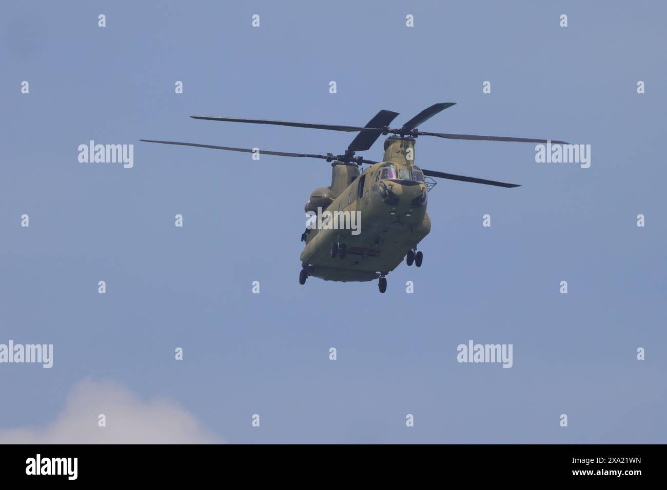 A military helicopter with landing gear deployed flying in the sky ...