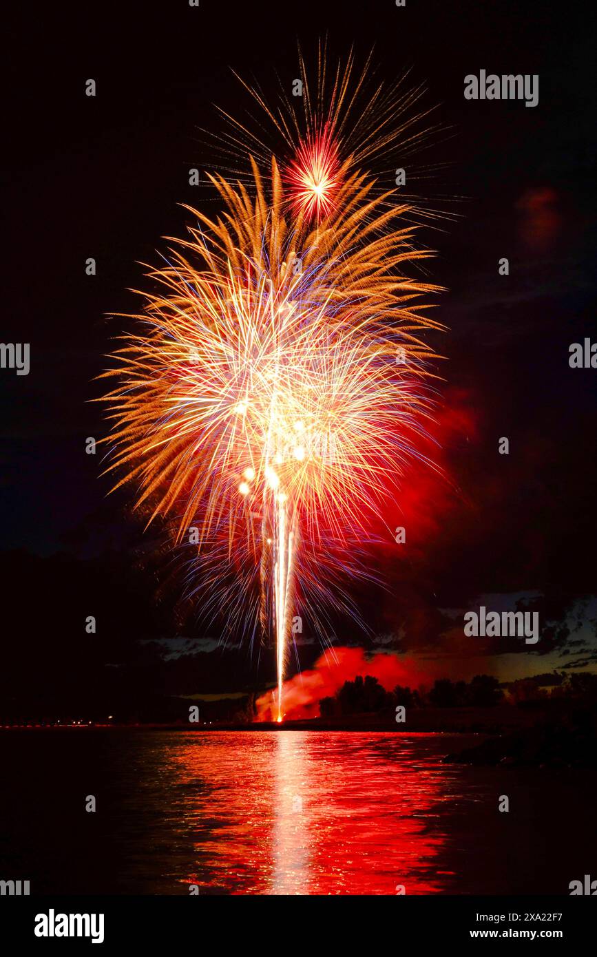 Vibrant fireworks reflecting on water at nighttime event Stock Photo ...