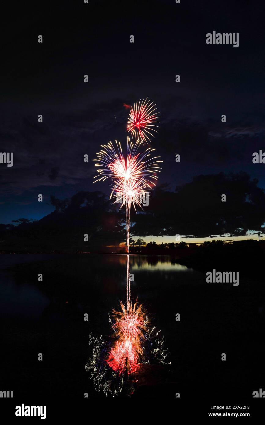 Colorful fireworks light up the night sky over water and hills Stock ...