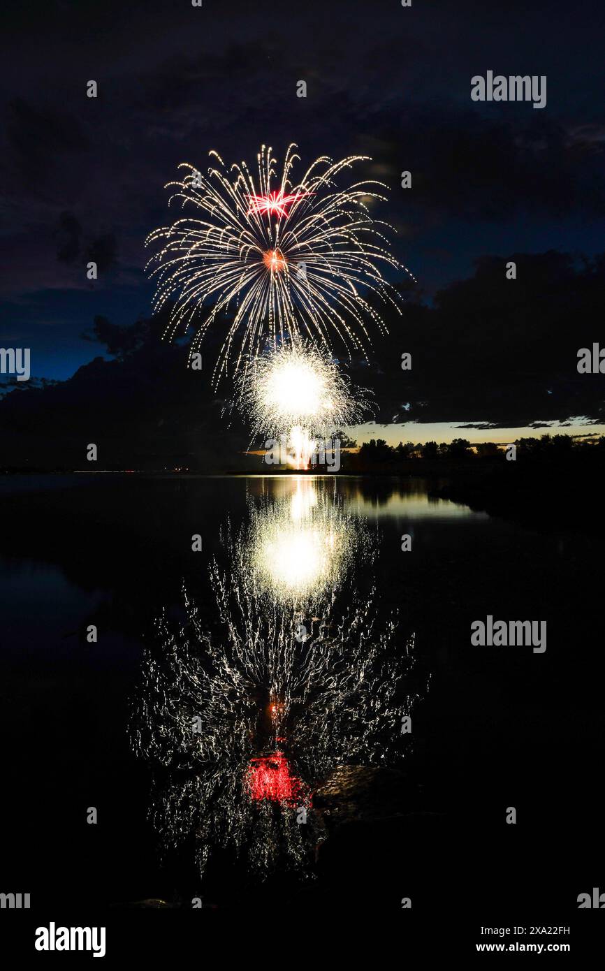 Colorful fireworks burst in the night sky, casting reflections on the ...