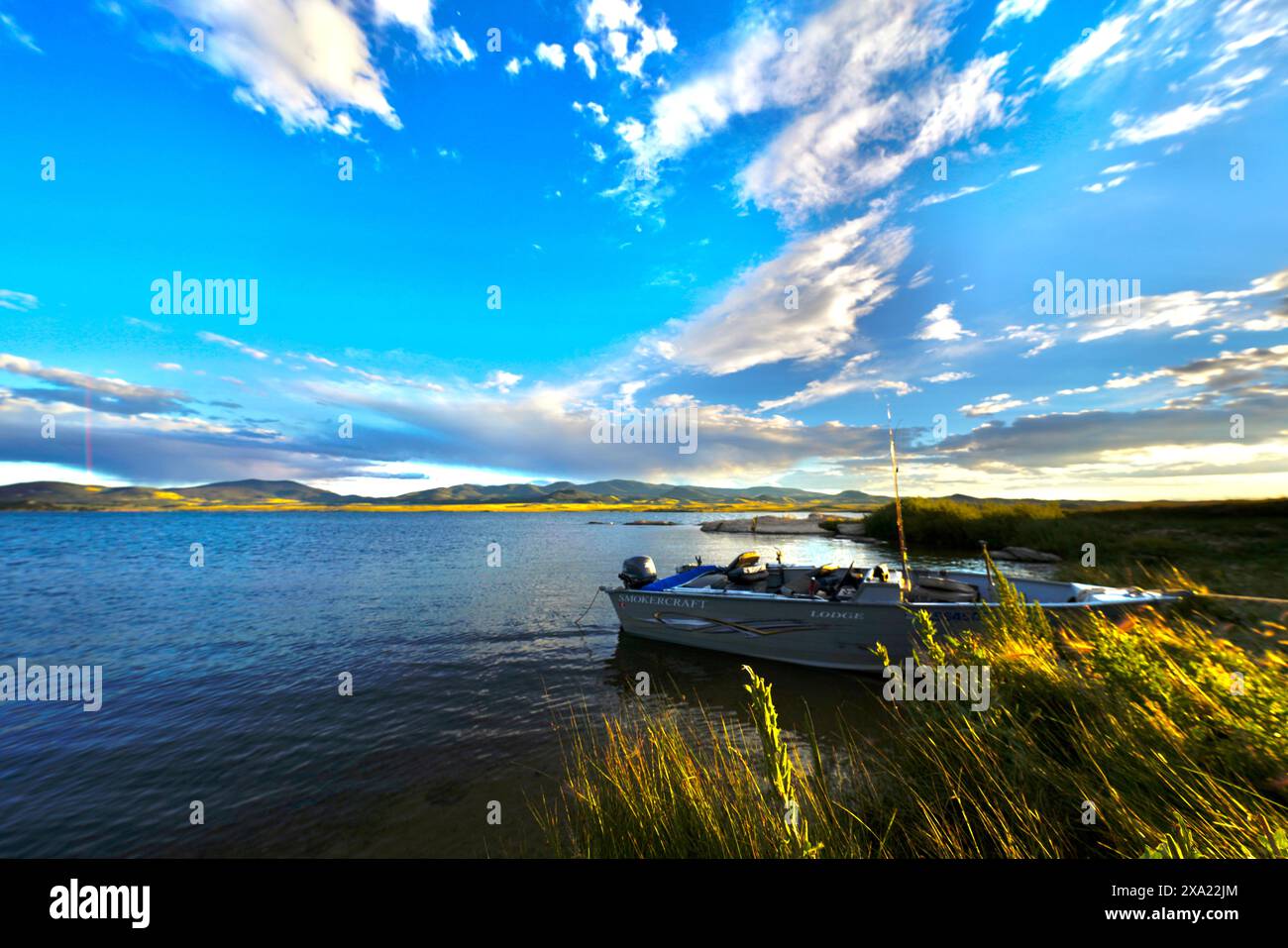 Boats on the water near grassy shore with distant mountains Stock Photo ...