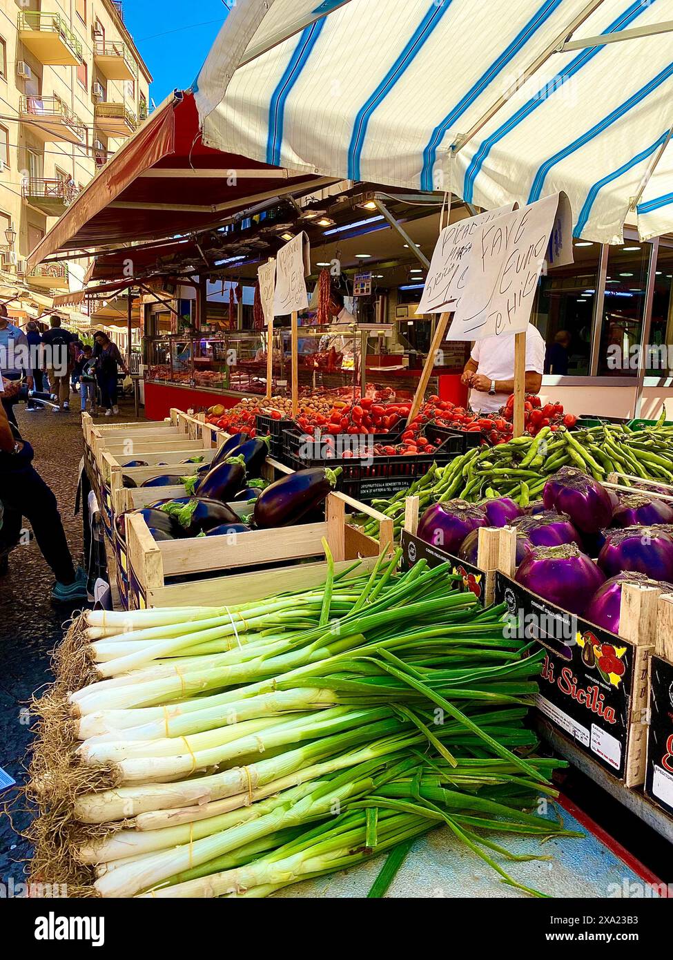 A farmers market vegetable stand by a building with assorted produce ...