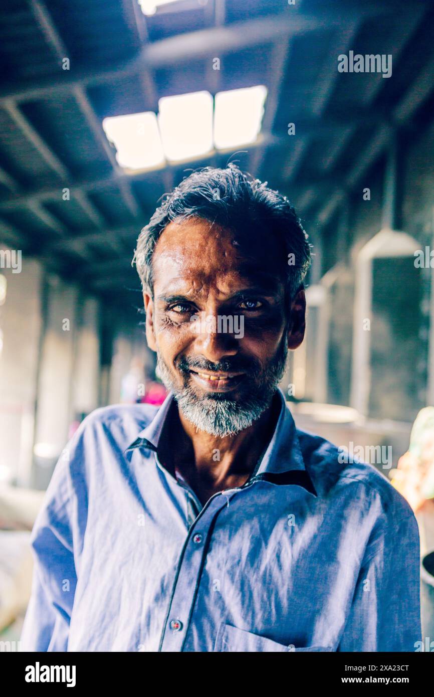 A man inside a Mumbai building, making eye contact with the camera in ...
