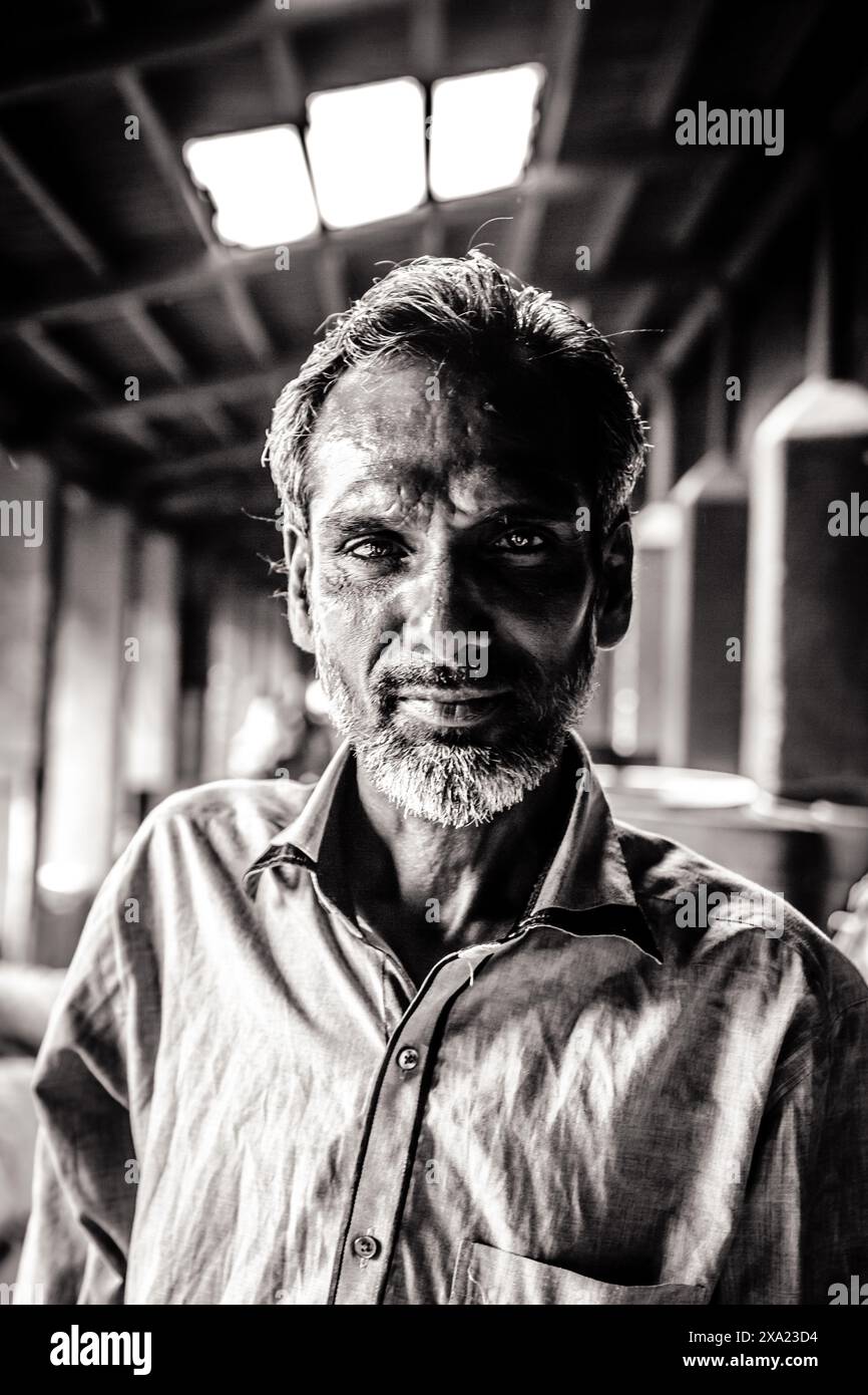 A man inside a Mumbai building, making eye contact with the camera in ...
