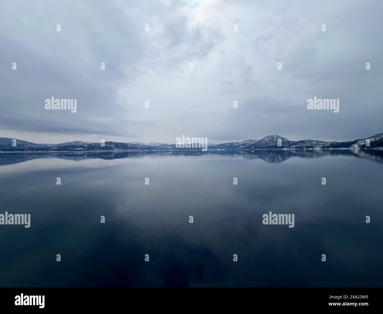 The beautiful view of Lake Tazawa with snowy mountains in the distance ...