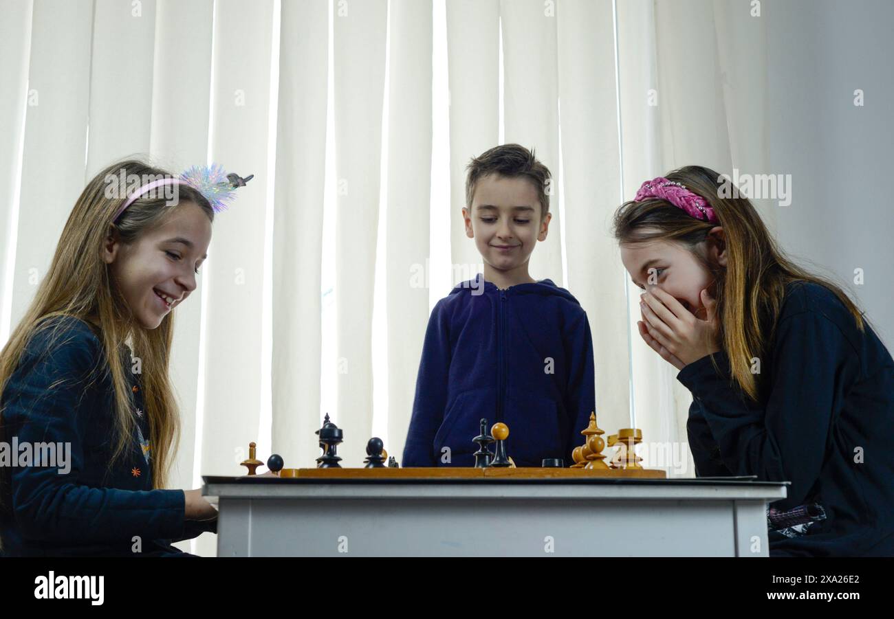 Three kids playing chess together Stock Photo - Alamy