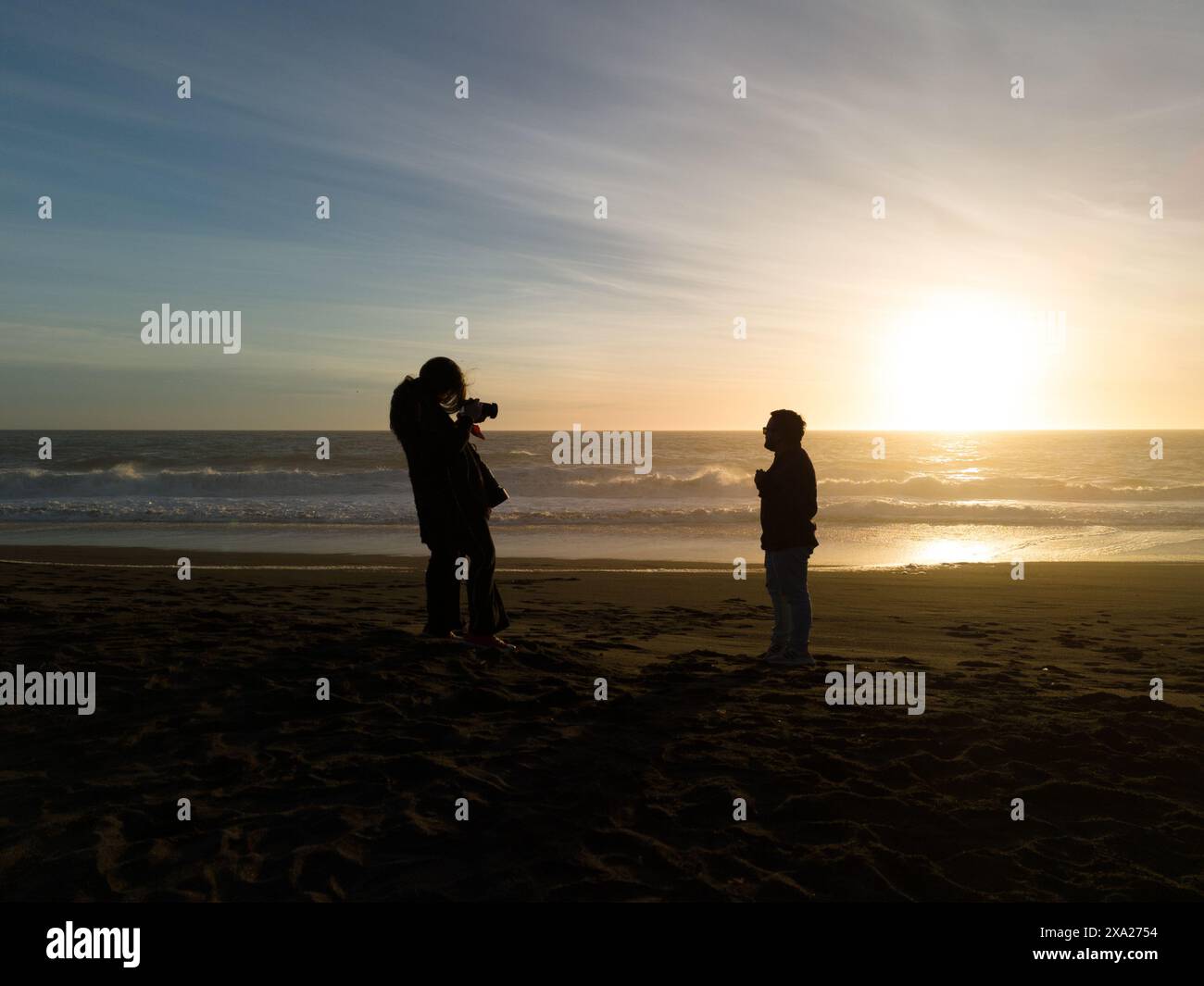 A female capturing a man on the beach during sunset Stock Photo - Alamy