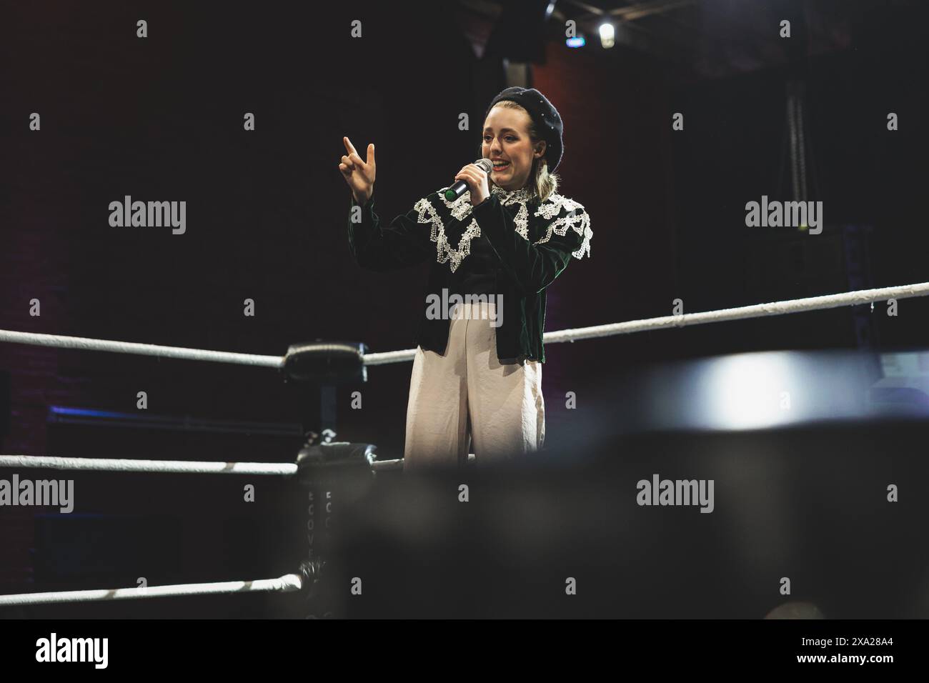 A female speaker holding a microphone, standing in a pro wrestling ring ...