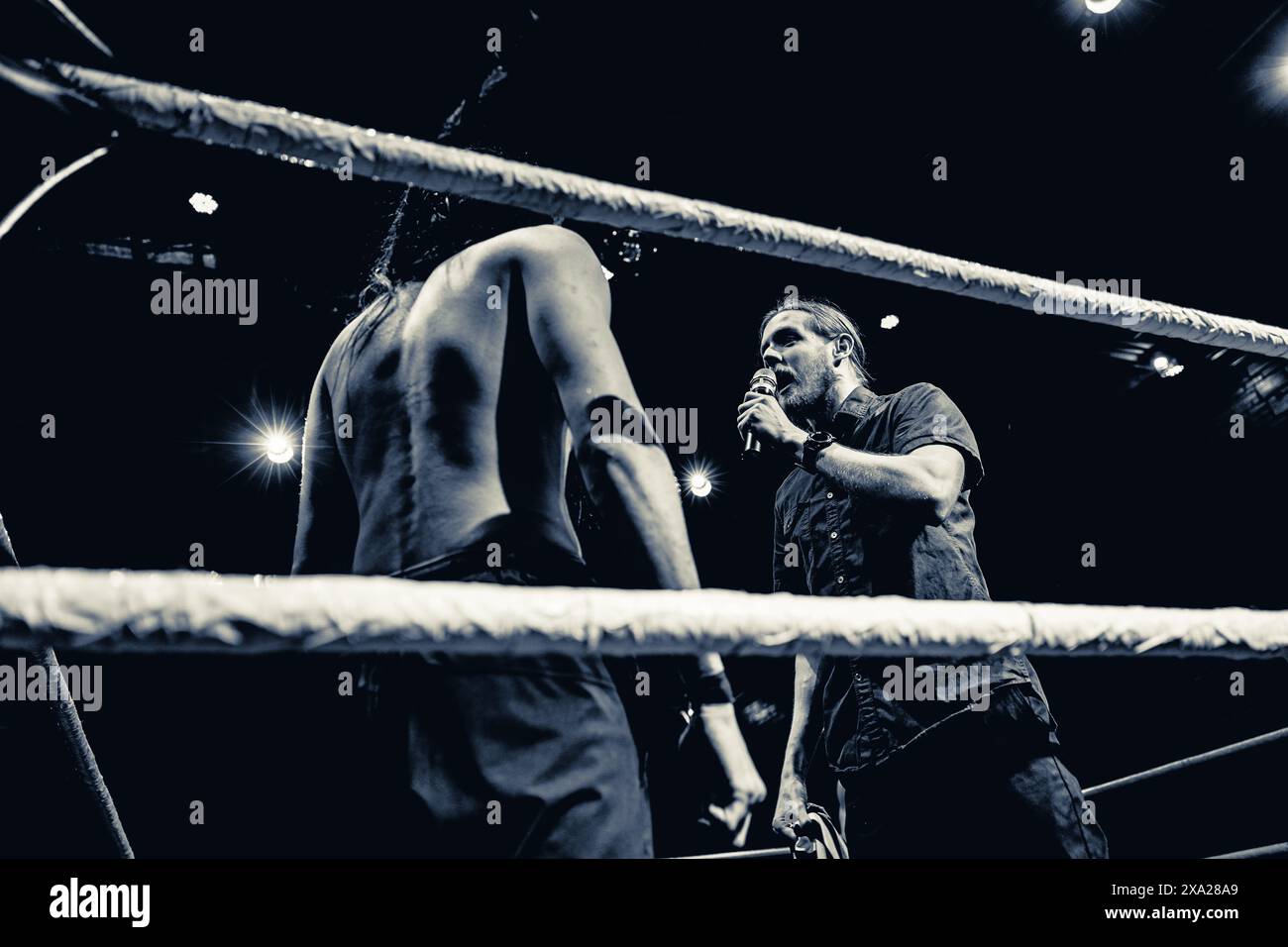 Two men wrestling in a ring, one with microphone. They aer haveing a ...
