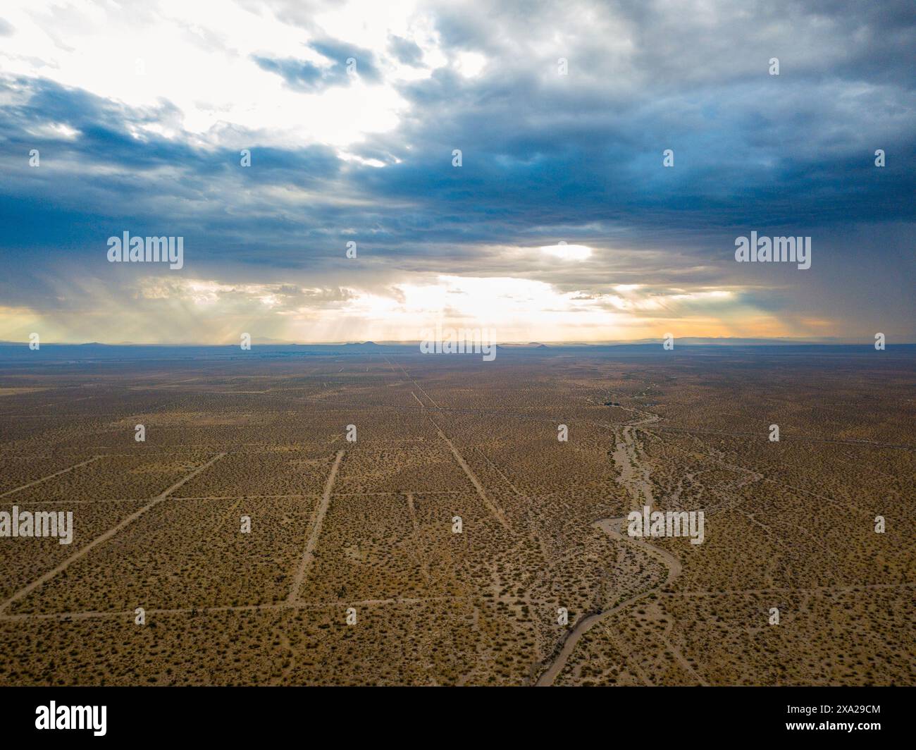 Desert landscape with road, dirt tracks, and distant sunset Stock Photo ...