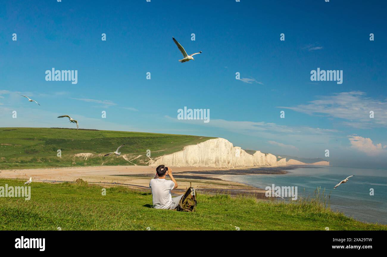 A man relaxing on a grassy hill by the ocean on the English Channel ...