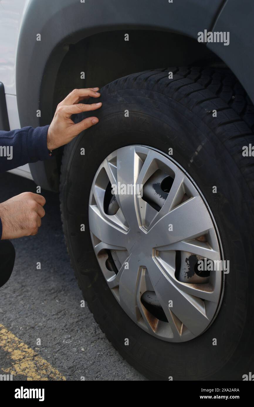 Man leaning on car, holding tire Stock Photo - Alamy