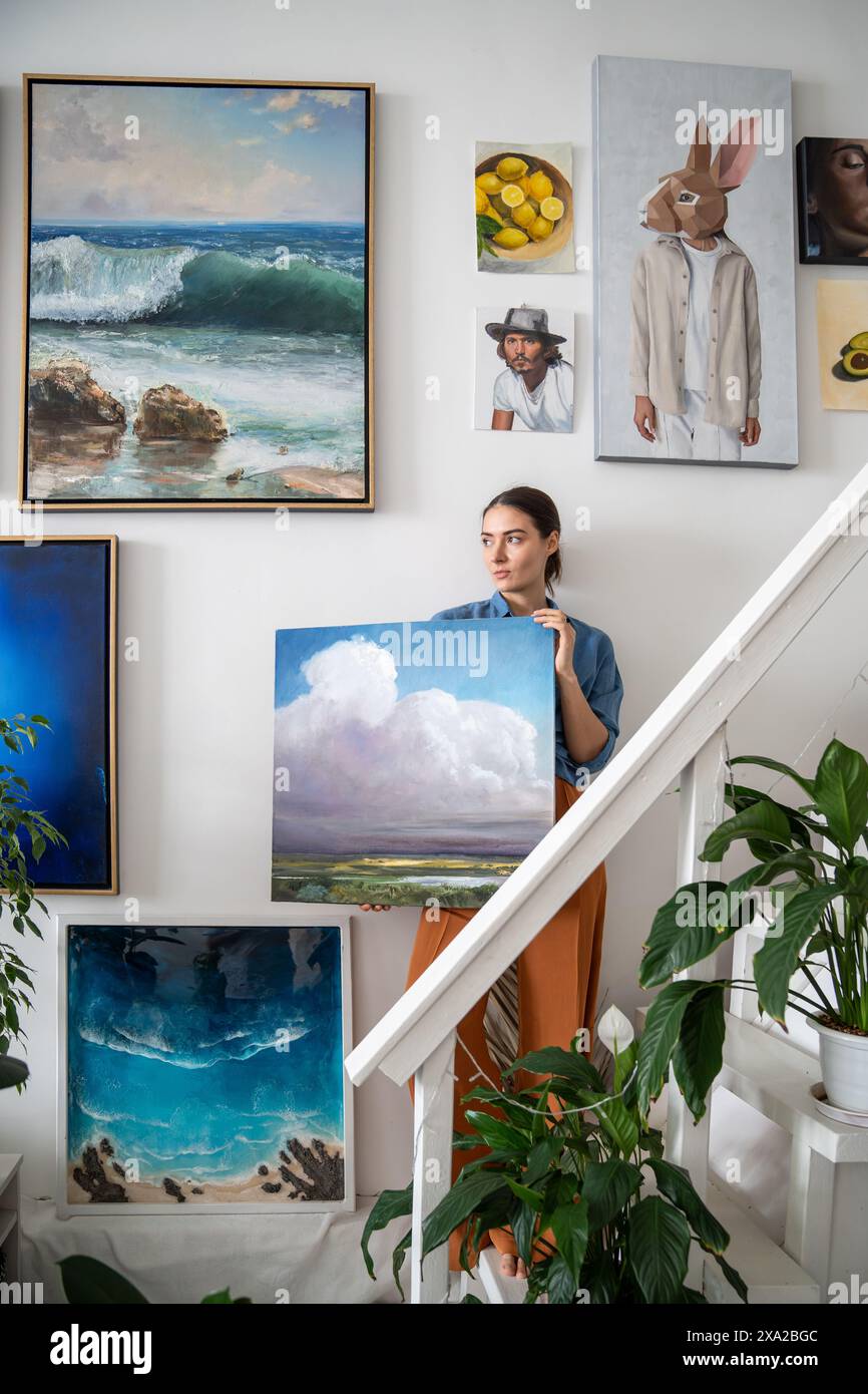 Serious pensive woman with canvas makes creative art composition from ...