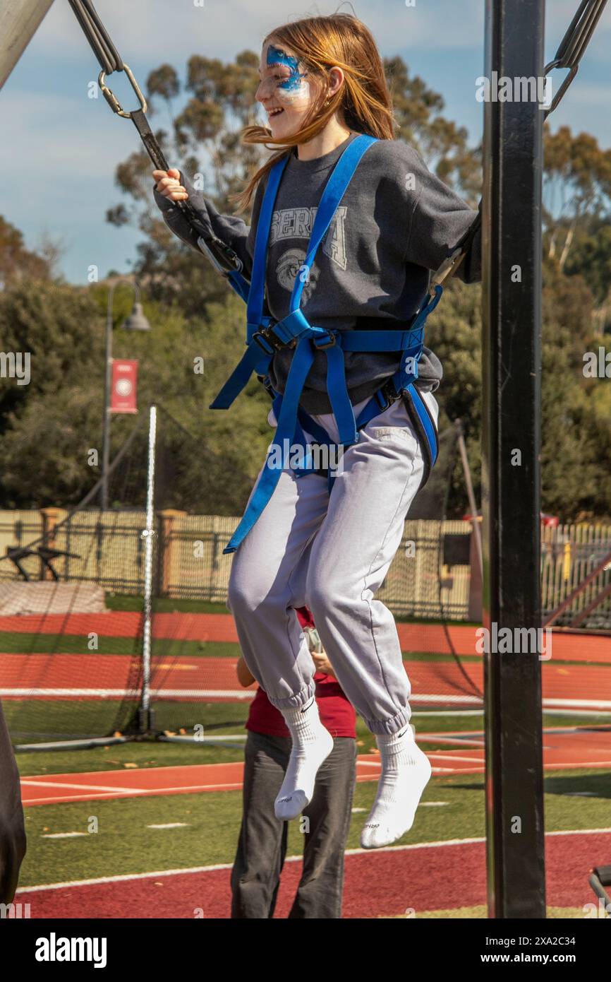 An athletic high school girl wears a harness as he swigs on a bungee ...