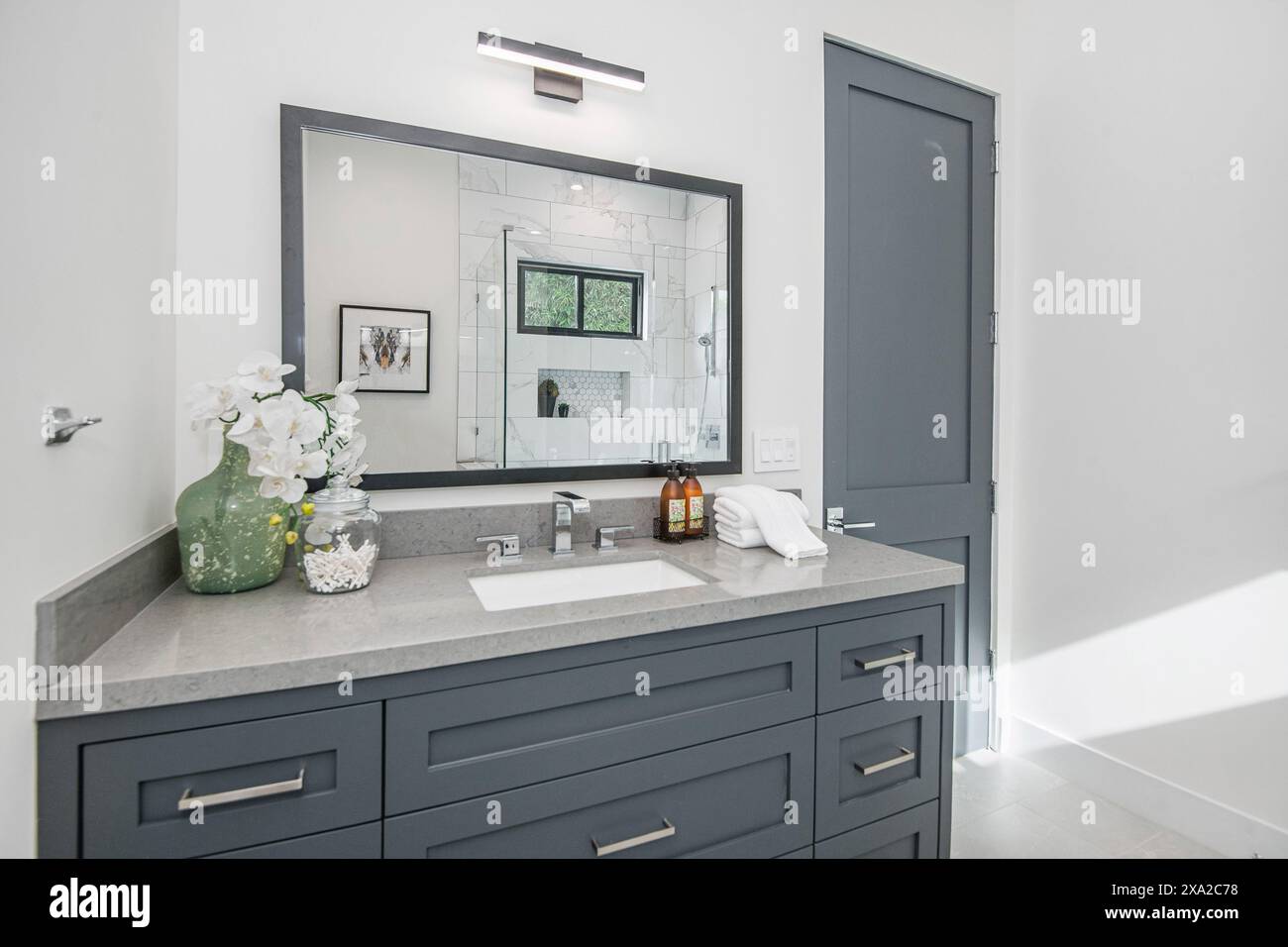 A gray bathroom sink and shower stall in a modern new construction home ...