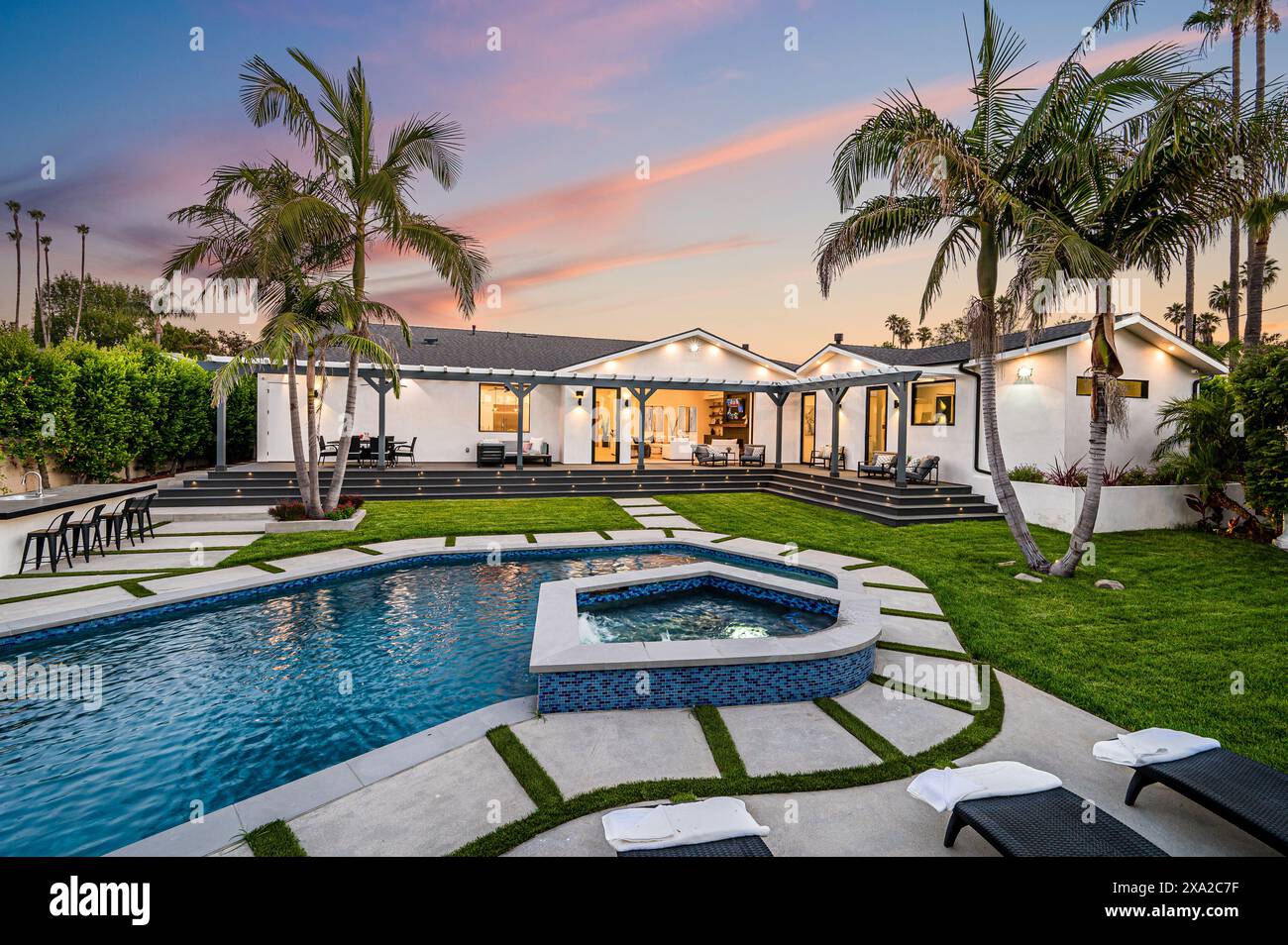 A backyard pool in a verdant garden setting in a modern new ...