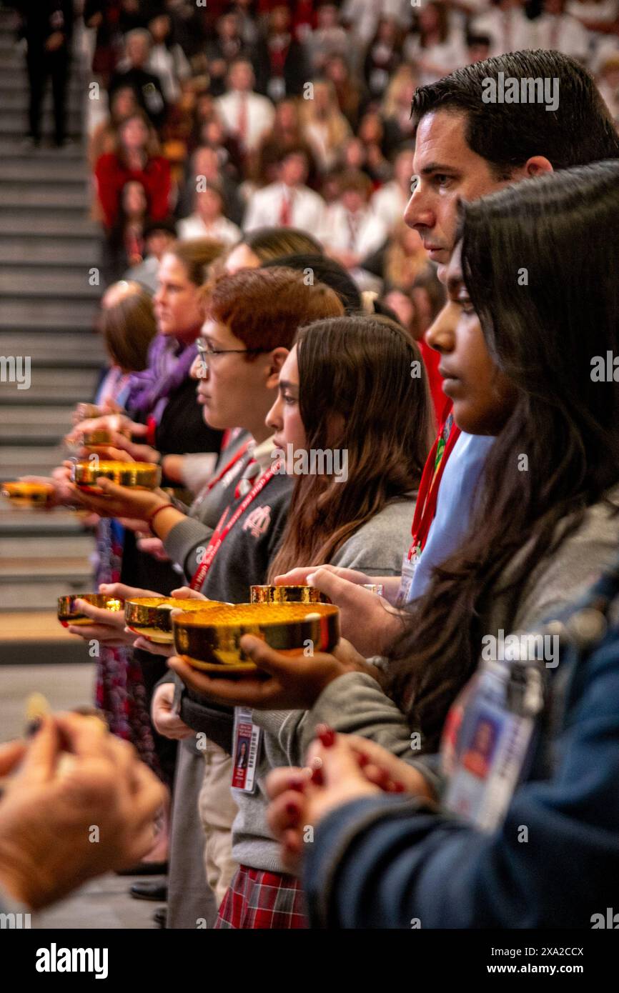 Multiracial students at a Southern California Catholic high school hold bowls of communion ...